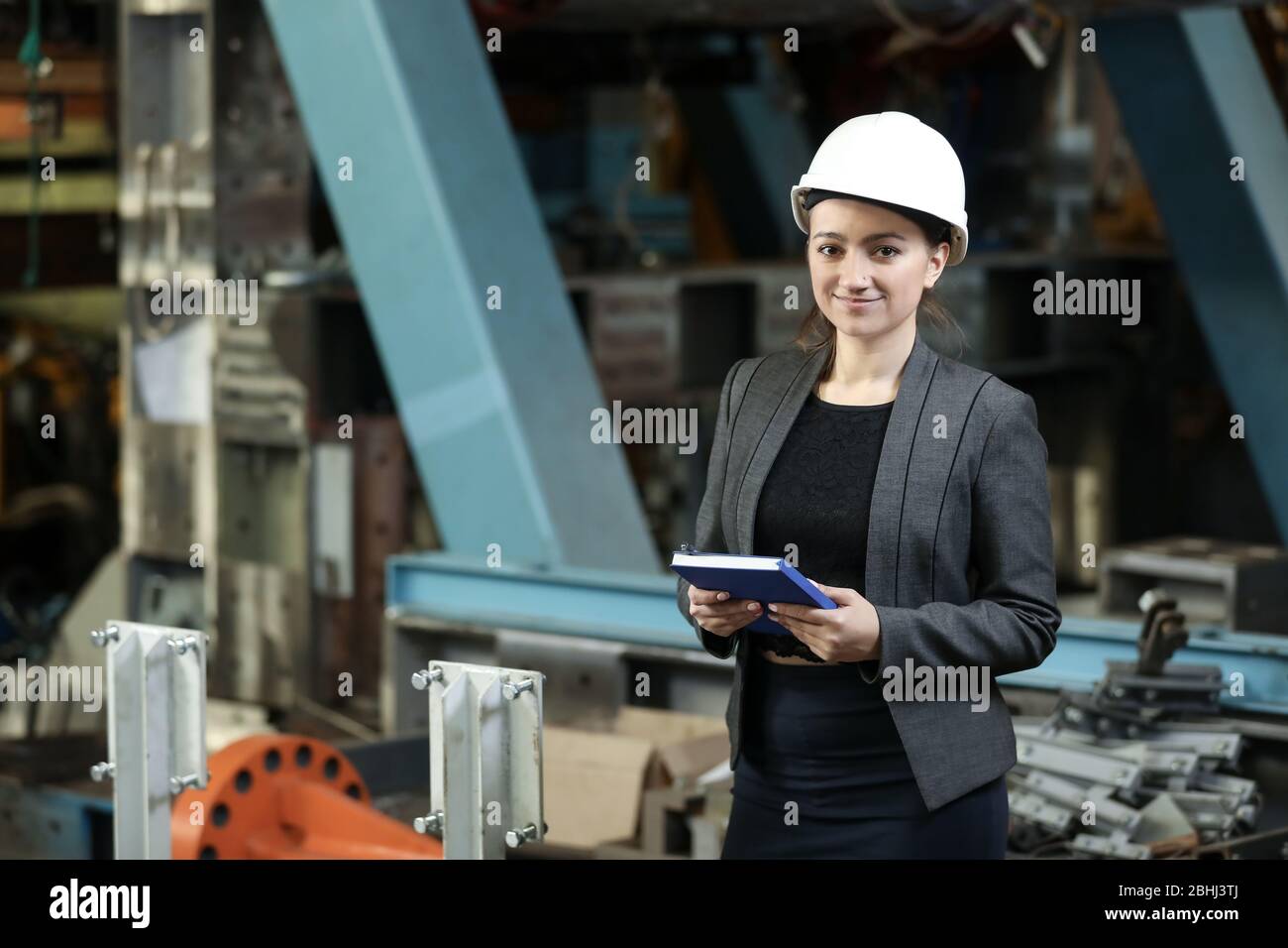 Portrait of a female factory manager in a white hard hat and business ...