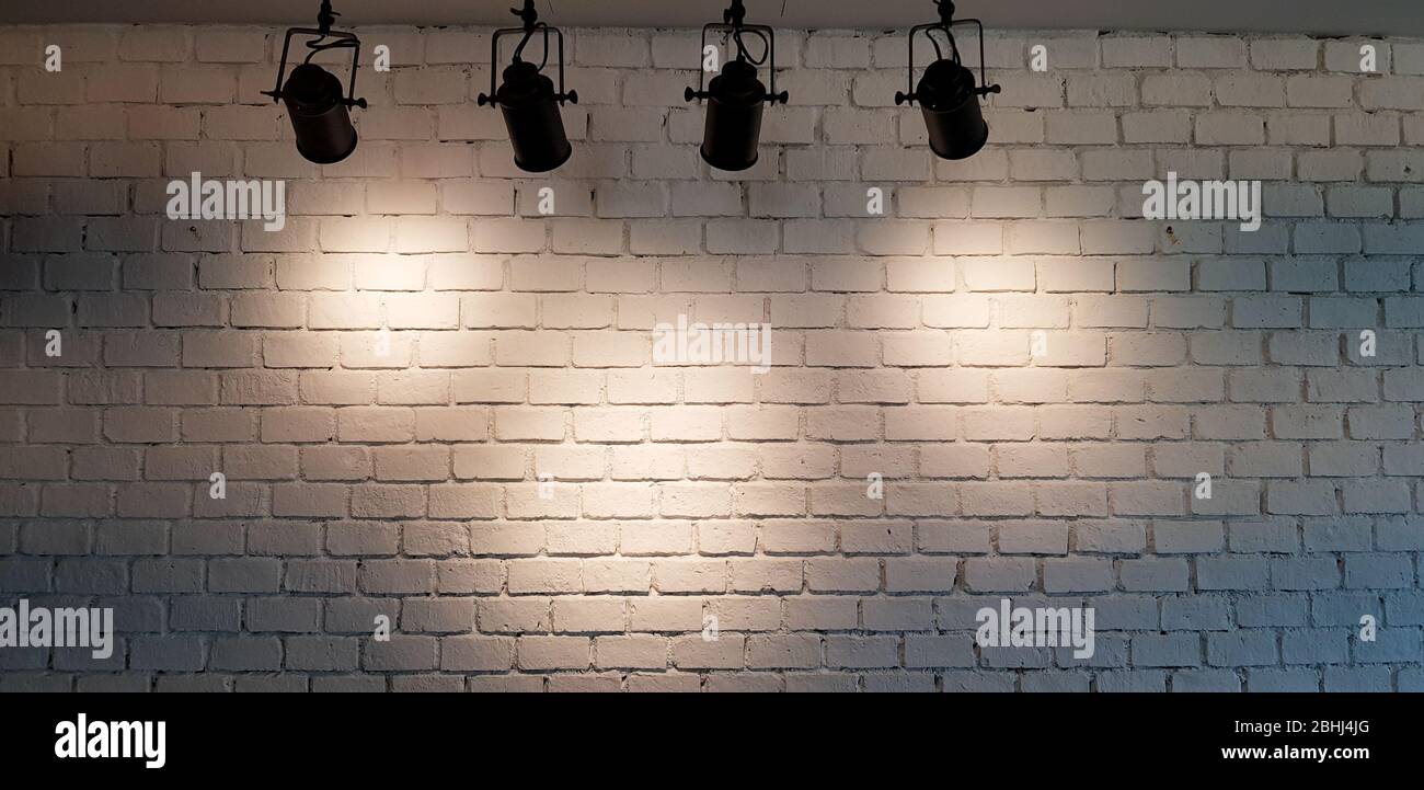 Hanging spotlight illuminate at white brick wall background with copy ...
