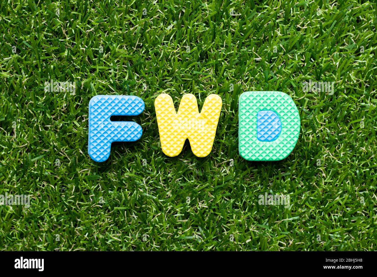 Toy foam letter in word FWD (Abbreviation of forward) on green grass ...