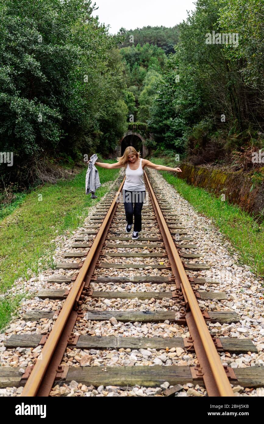Front view of a woman with her jacket in her hand walking along a train ...