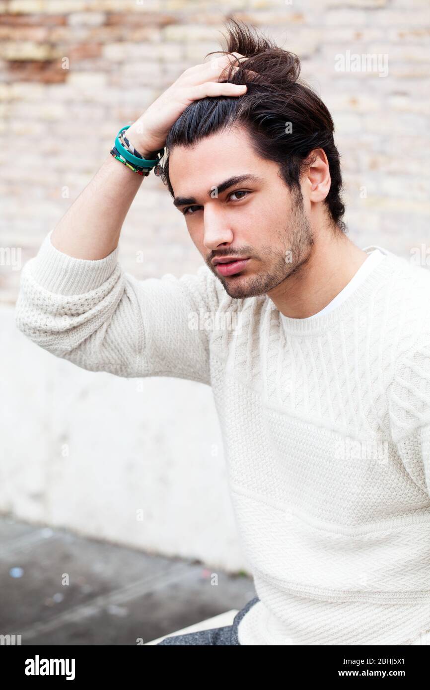 Young handsome man passing his hand through his hair. Trendy hair and ...