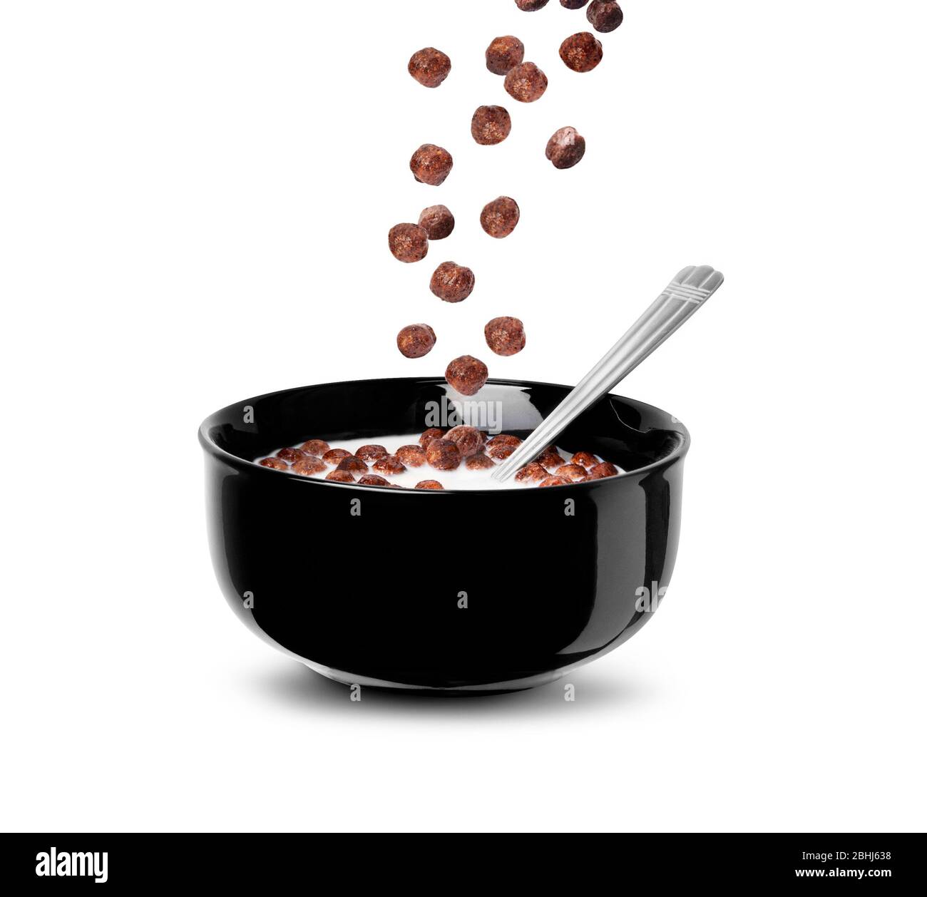 Falling chocolate cereal balls in milk in a black bowl isolated on a ...