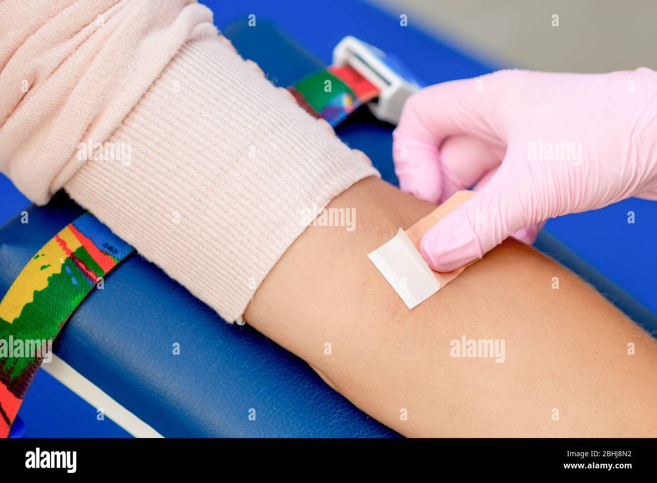 Nurse hand is glueing an adhesive plaster on arm after blood sampling ...