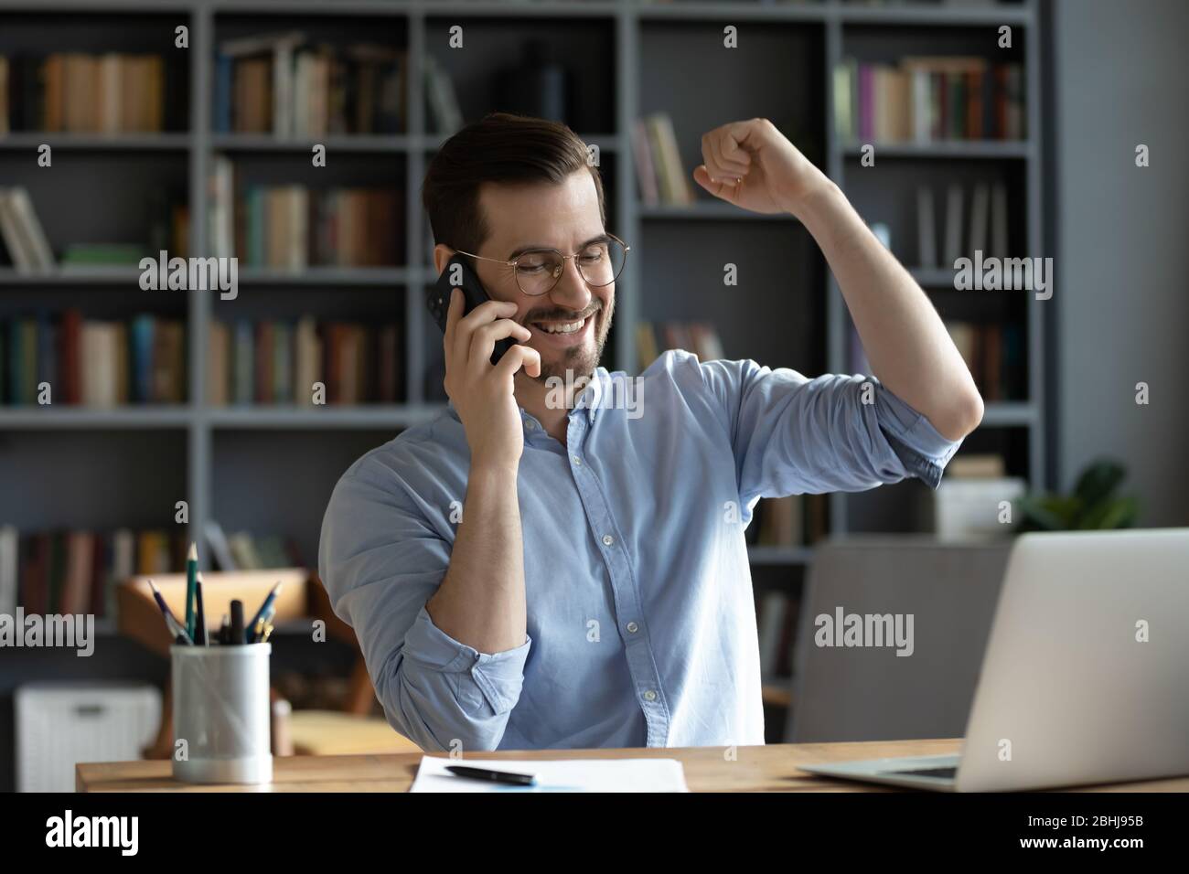 Smiling satisfied businessman making phone call, hearing good news ...