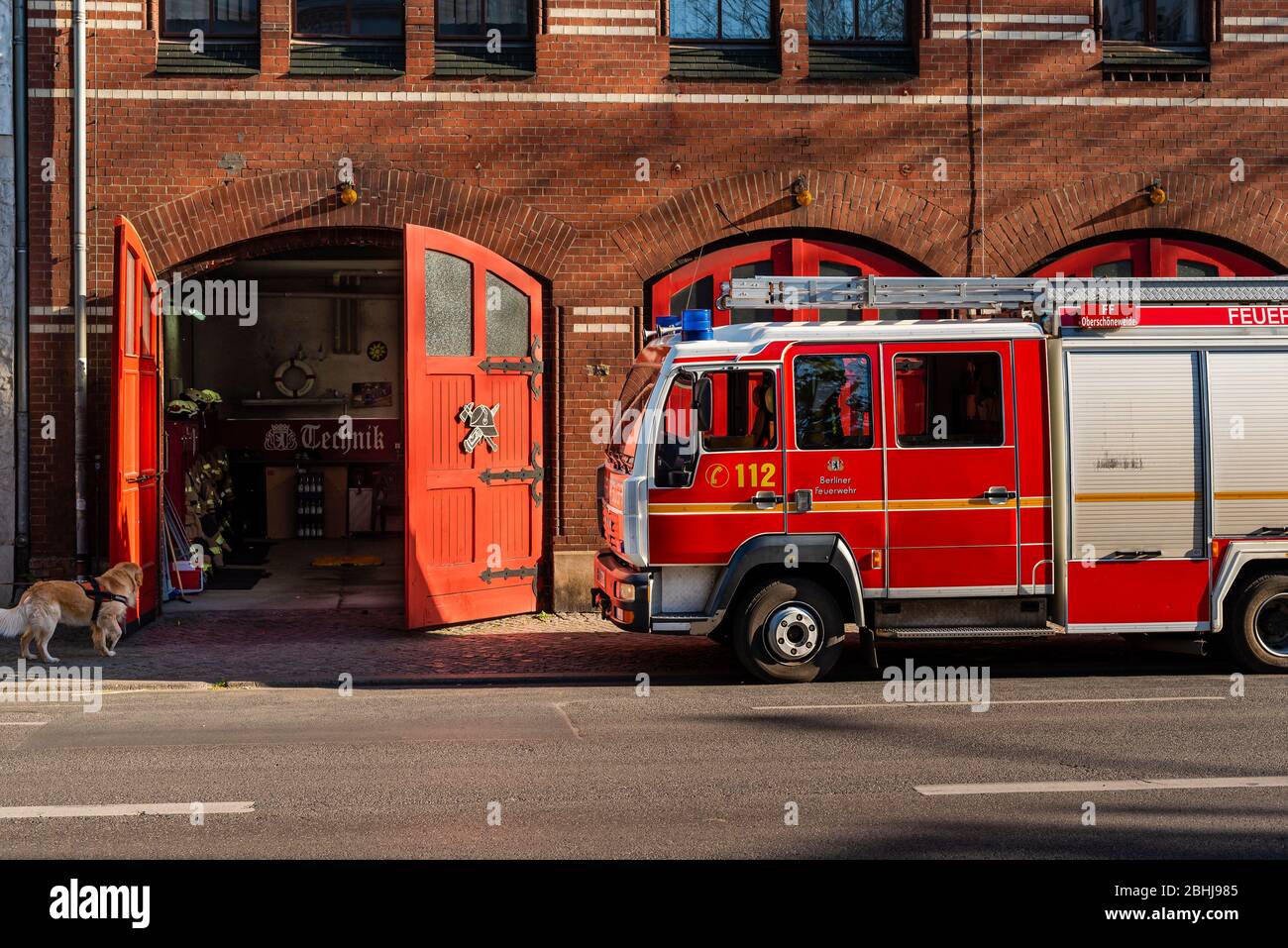 a fire engine stands in front of its fire station with the gate open ...