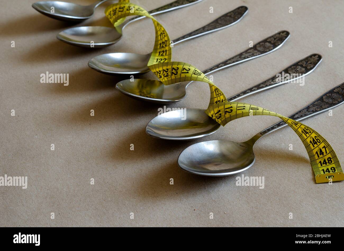 Metal spoons and tailor meter. A line of six cutlery and a yellow meter ...