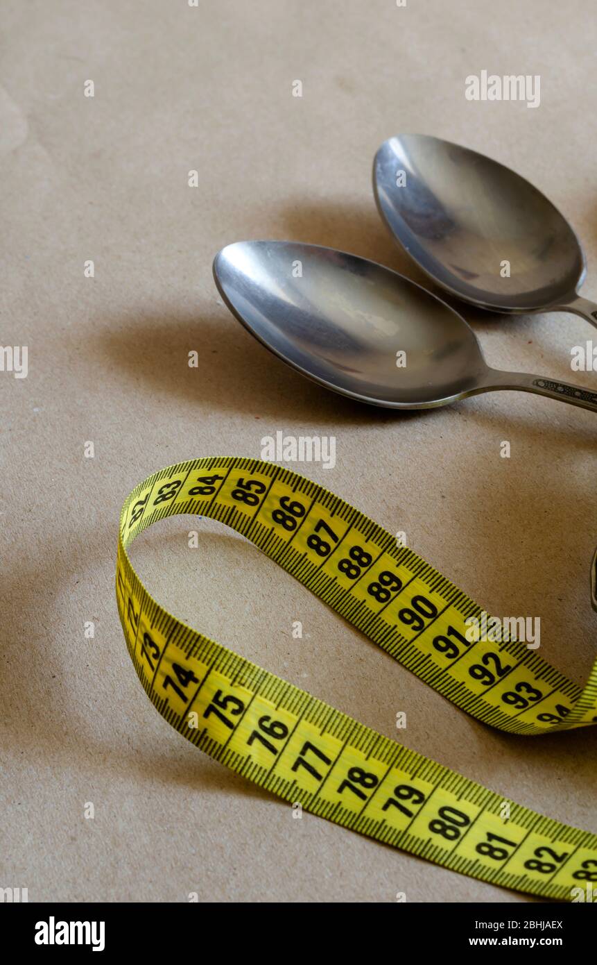 Tailor meter and two tablespoons. Metallic spoons with a yellow meter ...