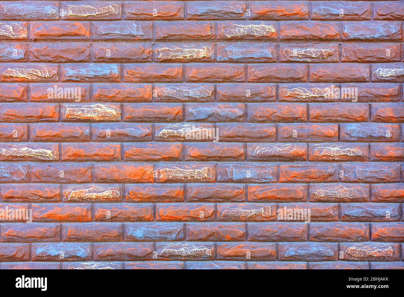The stone wall of smooth rectangular bricks is covered with red and ...