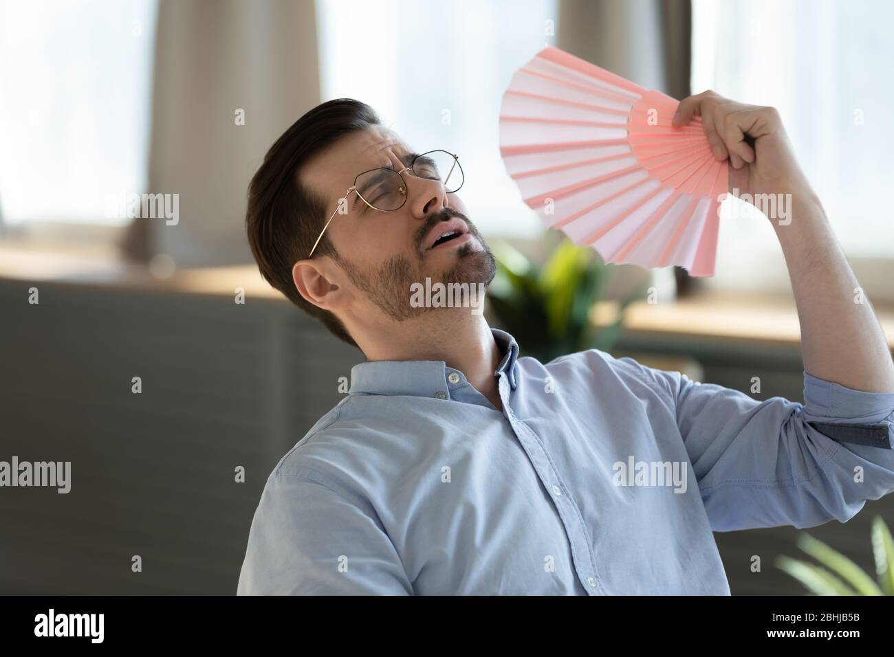 Overheated man in glasses waving paper fan, feeling unwell Stock Photo ...