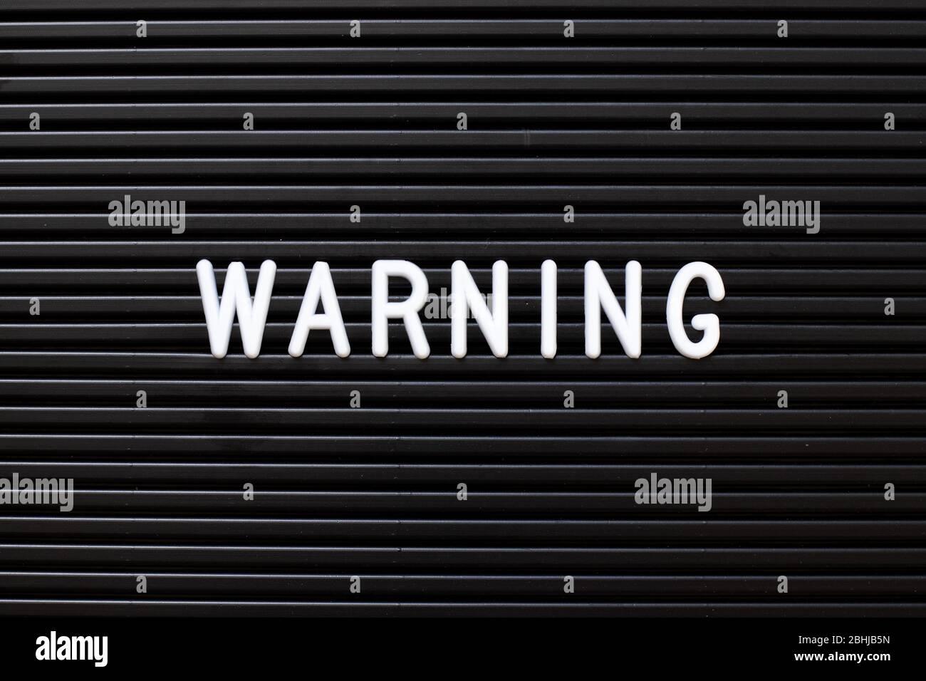 Black color felt letter board with white alphabet in word warning ...