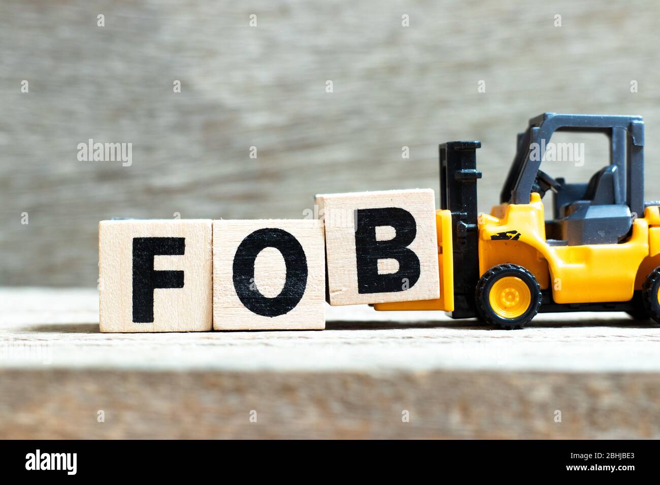 Toy forklift hold letter block B to complete word FOB (abbreviation of ...
