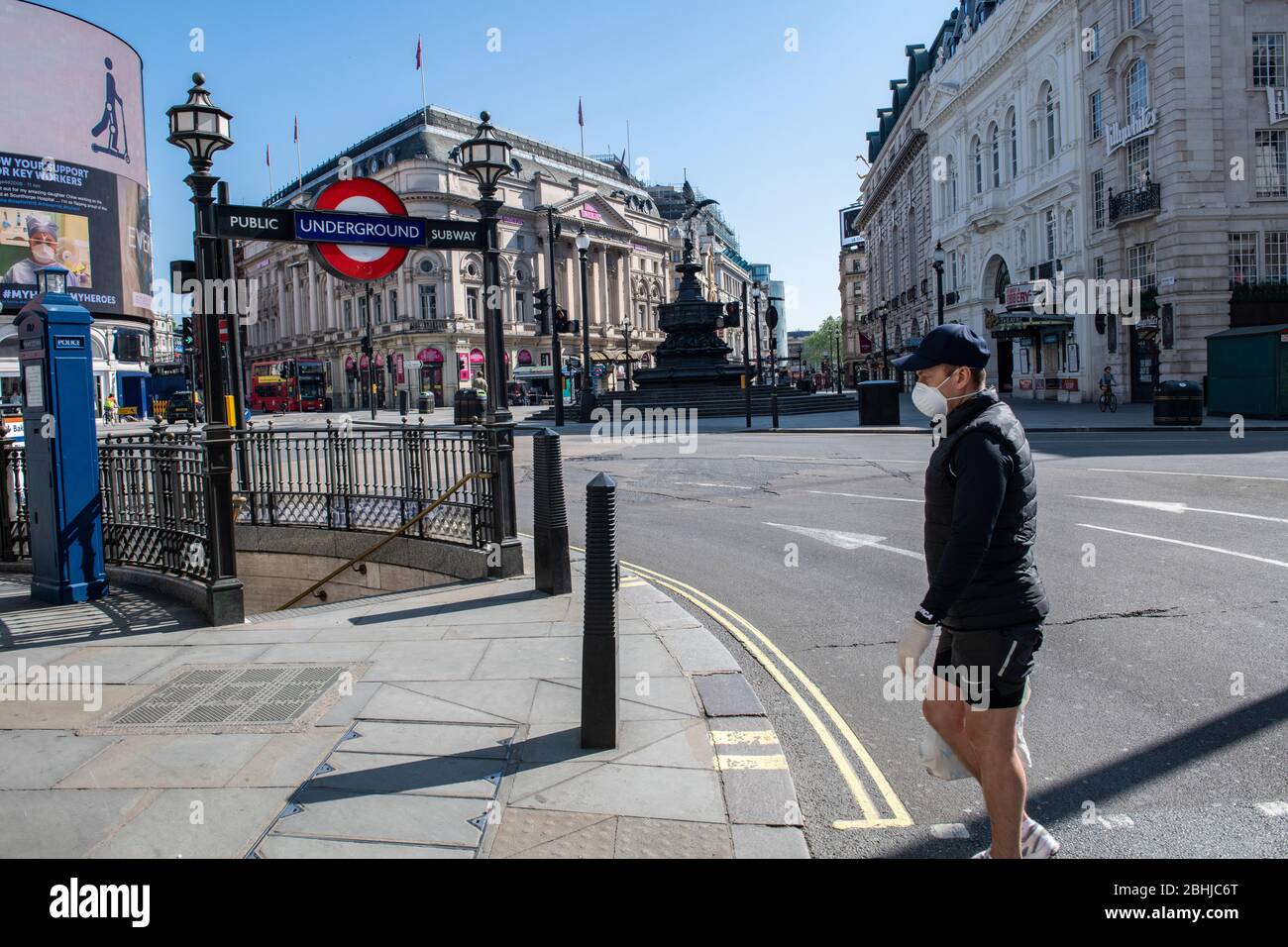 A man with a face mask walks across a deserted Piccadilly Circus in ...