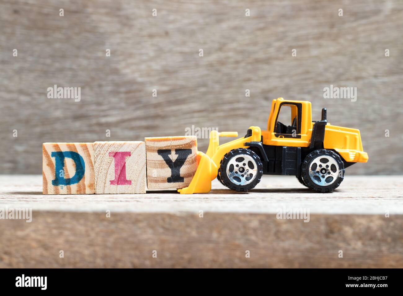 Toy bulldozer hold letter block Y to complete word DIY (abbreviation of ... Toy bulldozer hold letter block Y to complete word DIY (abbreviation of ...