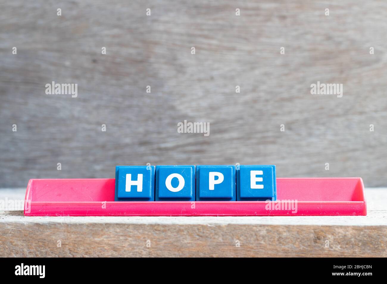 Tile letter on red rack in word hope on wood background Stock Photo - Alamy