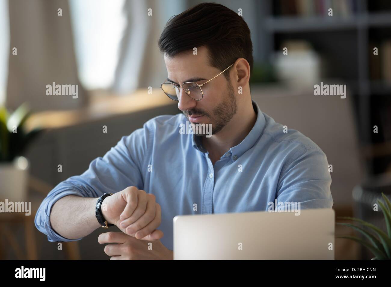 Confident businessman checking time, looking at wrist watch Stock Photo ...