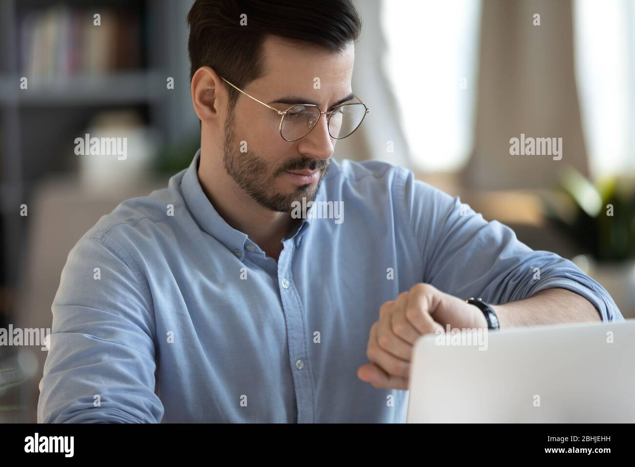 Confident businessman wearing glasses looking at wrist watch, checking ...