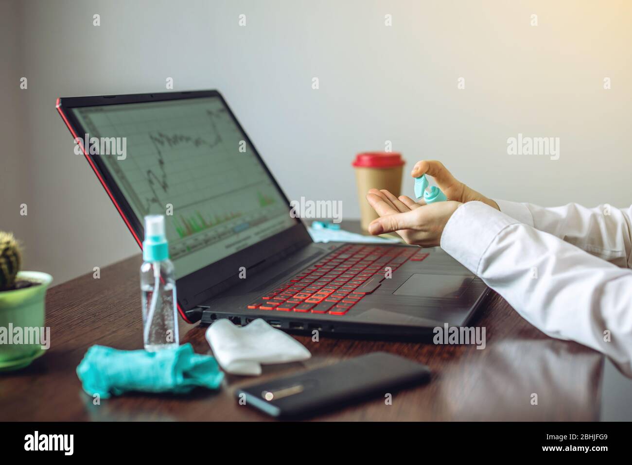 A woman applying a disinfectant to her hands before working at the ...