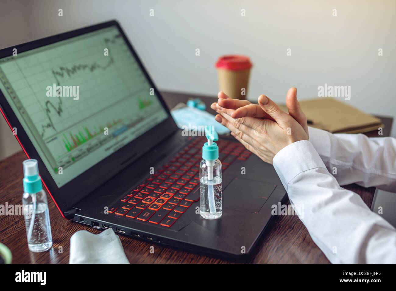 A woman applying a disinfectant to her hands before working at the ...