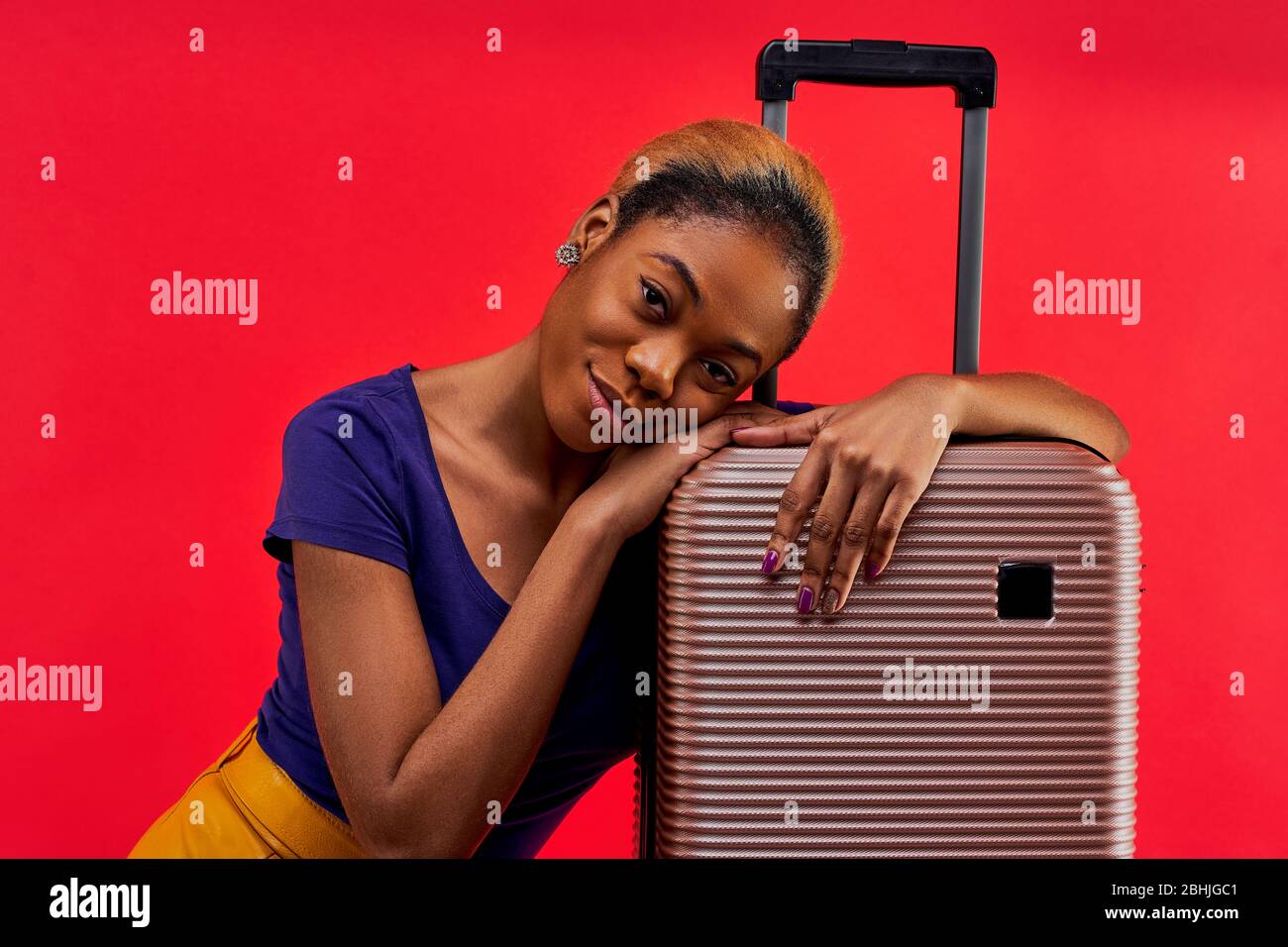 Woman with a wide smile hugs a luggage with a handle by her hands Stock ...