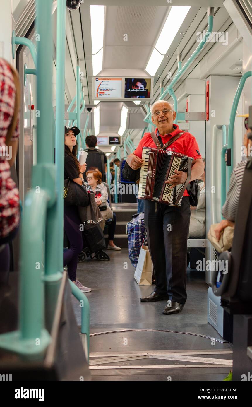 An elderly busker performing inside a TPG tram with his accordion at ...