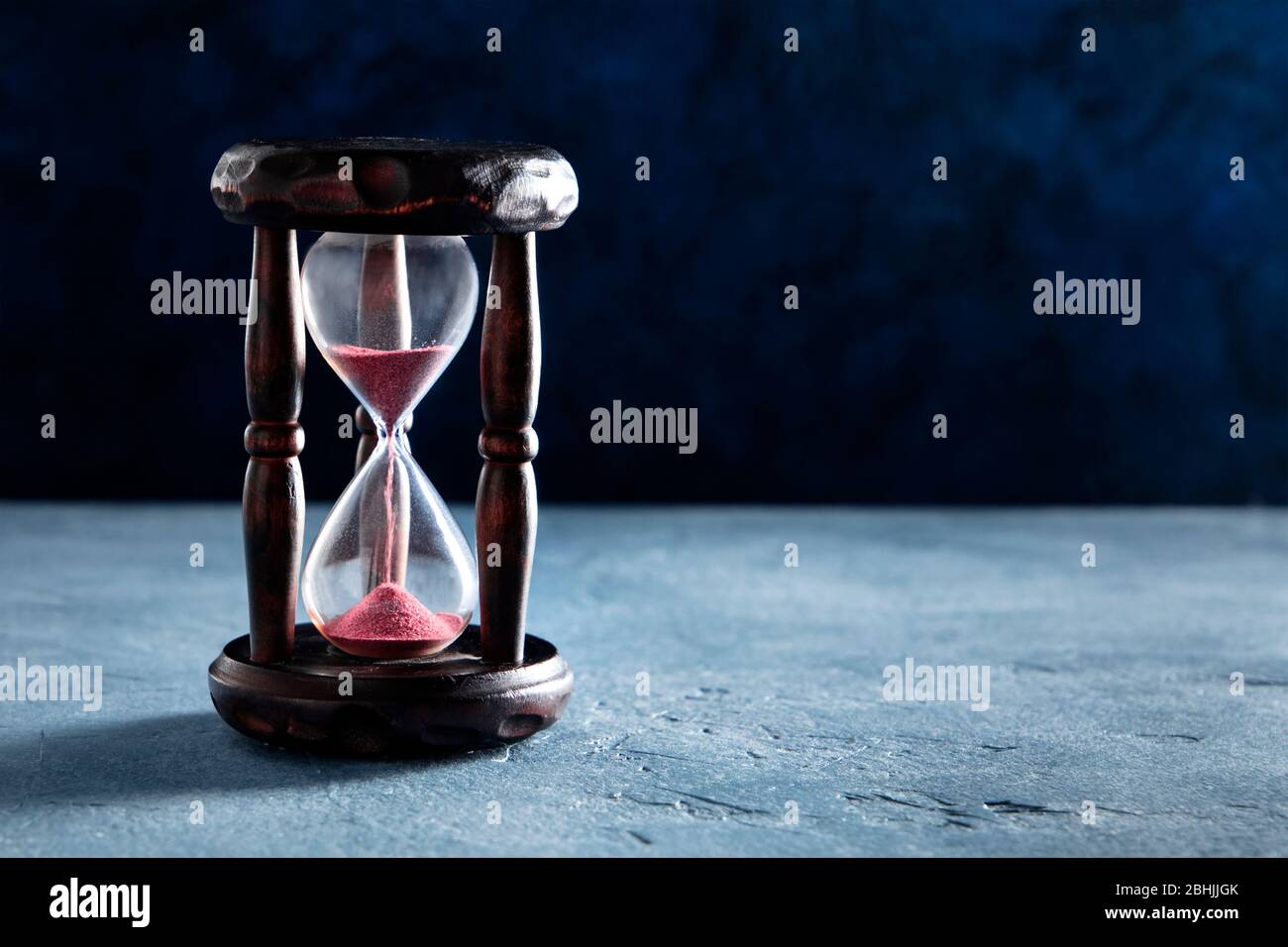 Time concept. An hourglass with sand falling through, on a dark ...