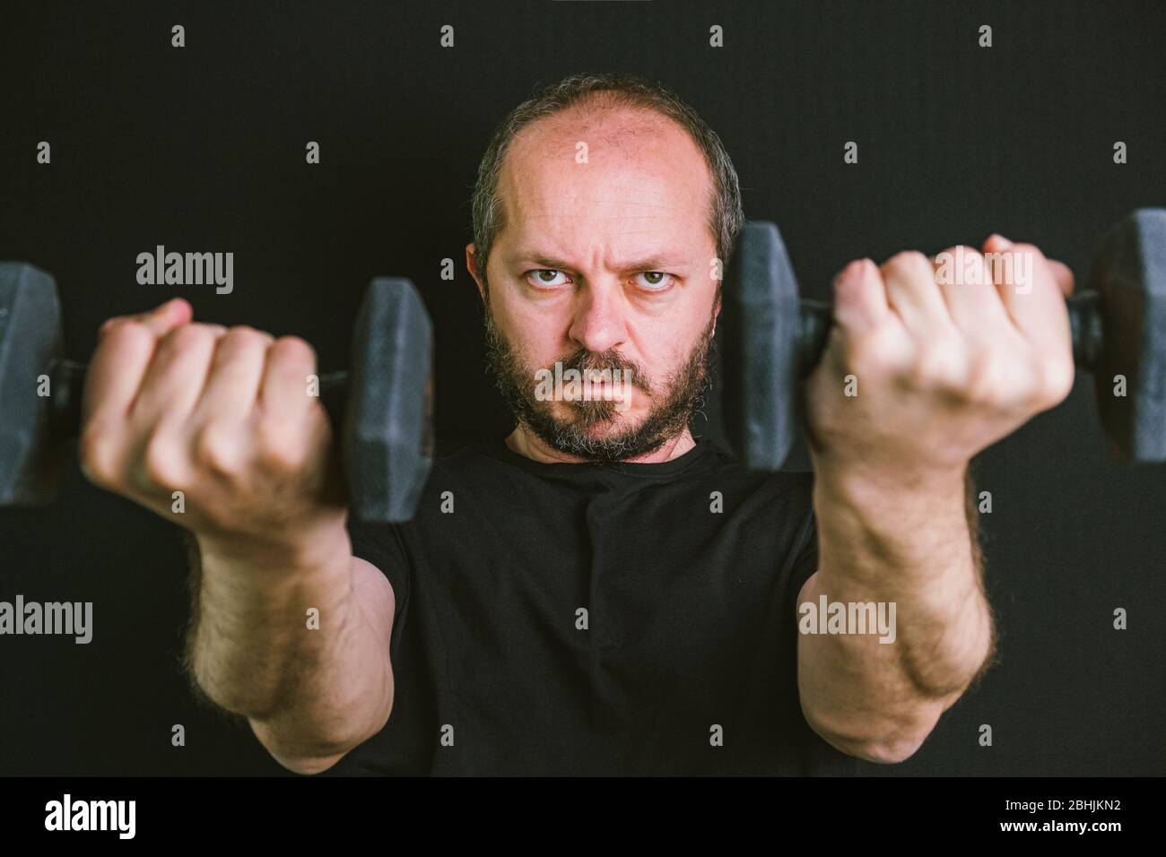 Adult man training muscles at home gym, doing biceps with dumbbell ...