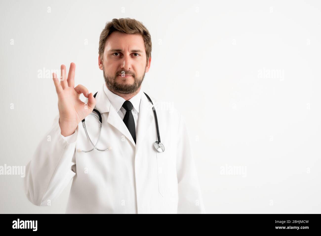 Portrait of male doctor with stethoscope in medical uniform showing OK ...