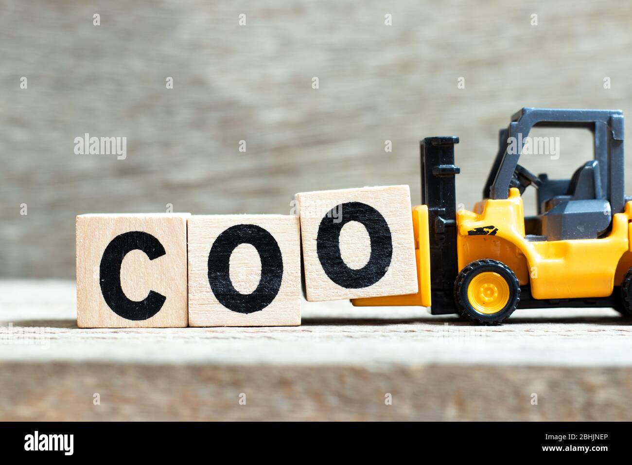 Toy forklift hold letter block O to complete word COO (abbreviation ...