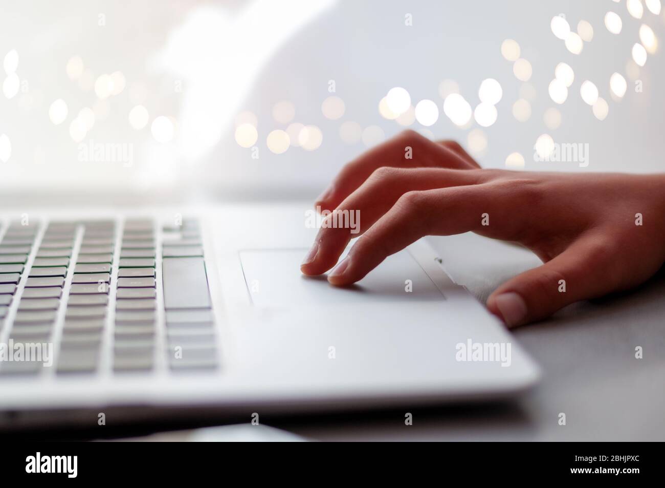 hand on laptop computer trackpad ith bokeh background. room for text ...