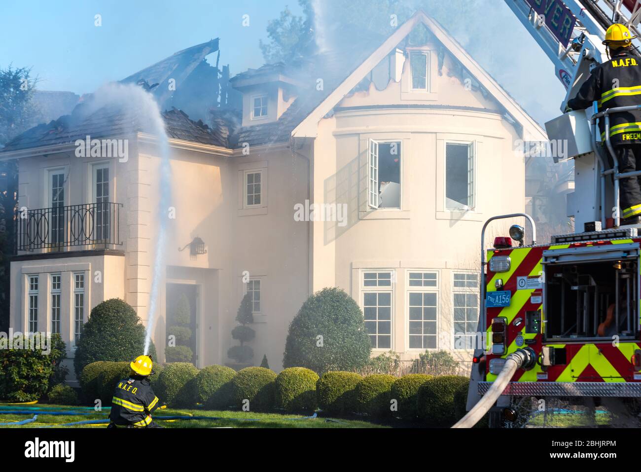 Two uniformed fire fighters battling a house fire Stock Photo - Alamy