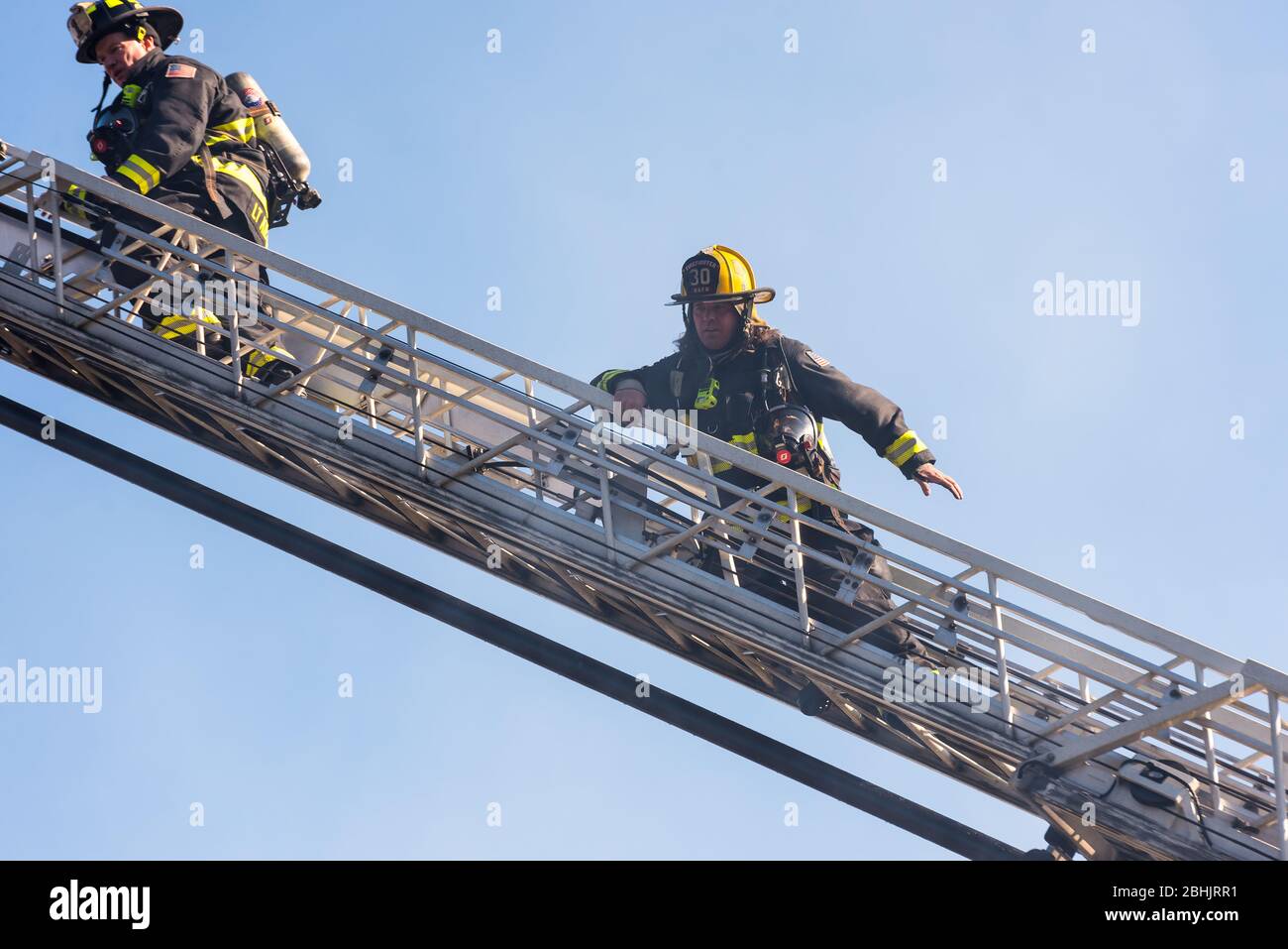 Two uniformed firefighters at the top of a ladder fighting a fire Stock ...