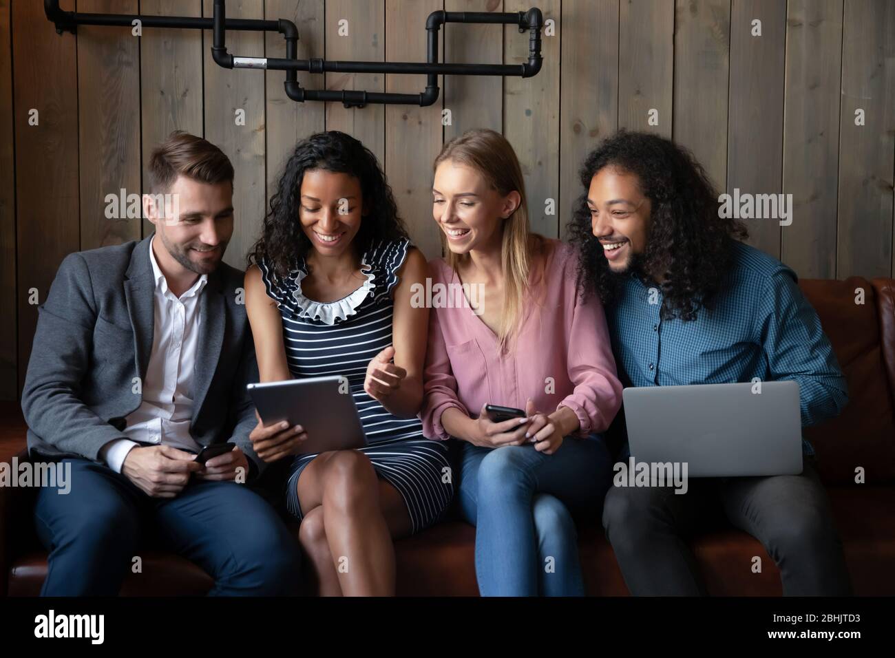 Happy young people have fun using modern devices in cafe Stock Photo ...