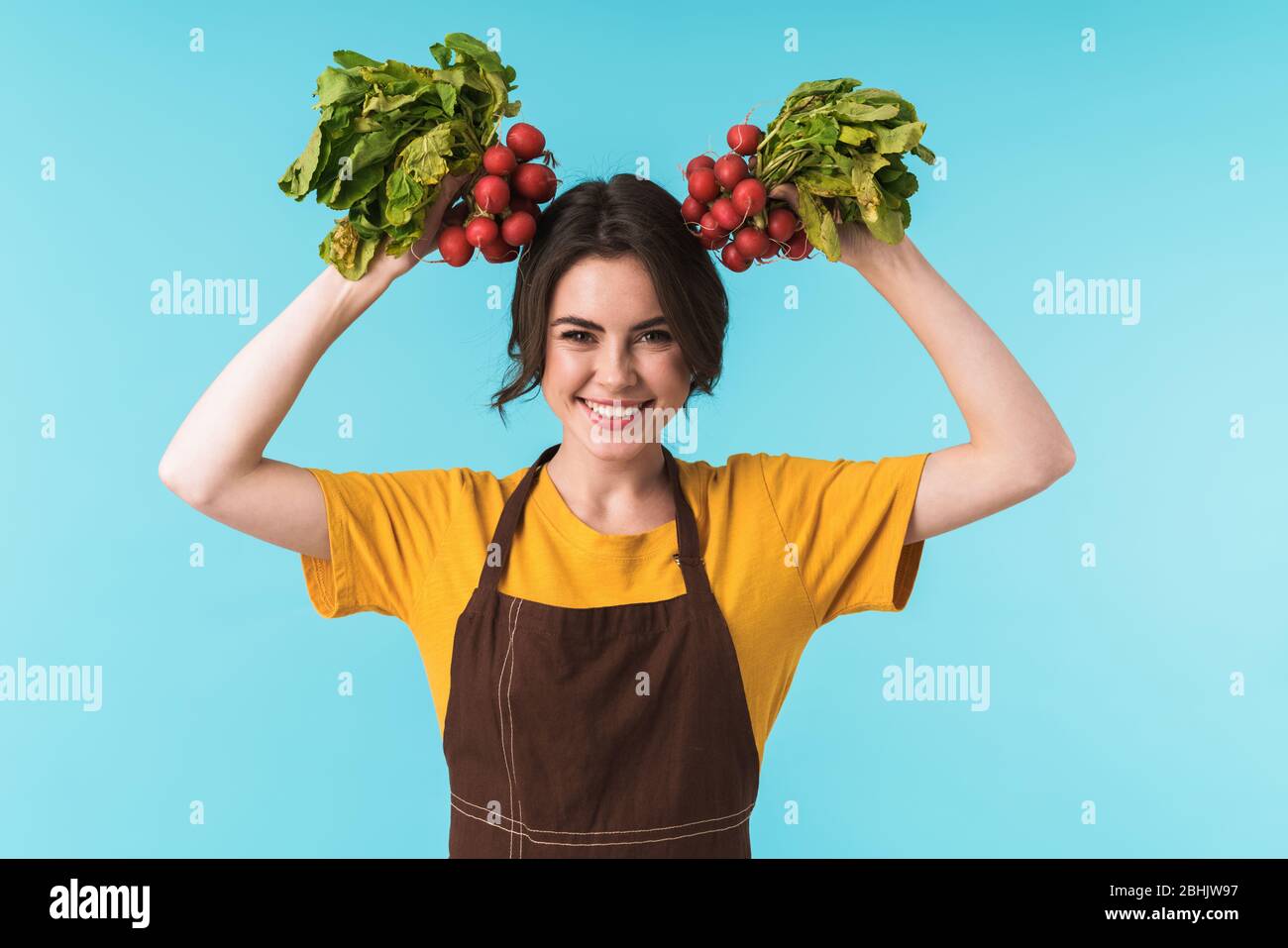 Image of cute positive young woman chef holding radish isolated over ...