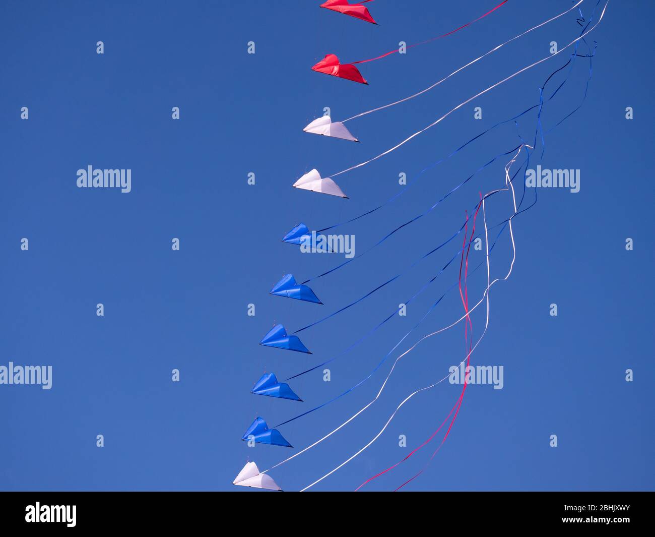 Stack of red, white an blue dual line stunt kites on a blue sky ...