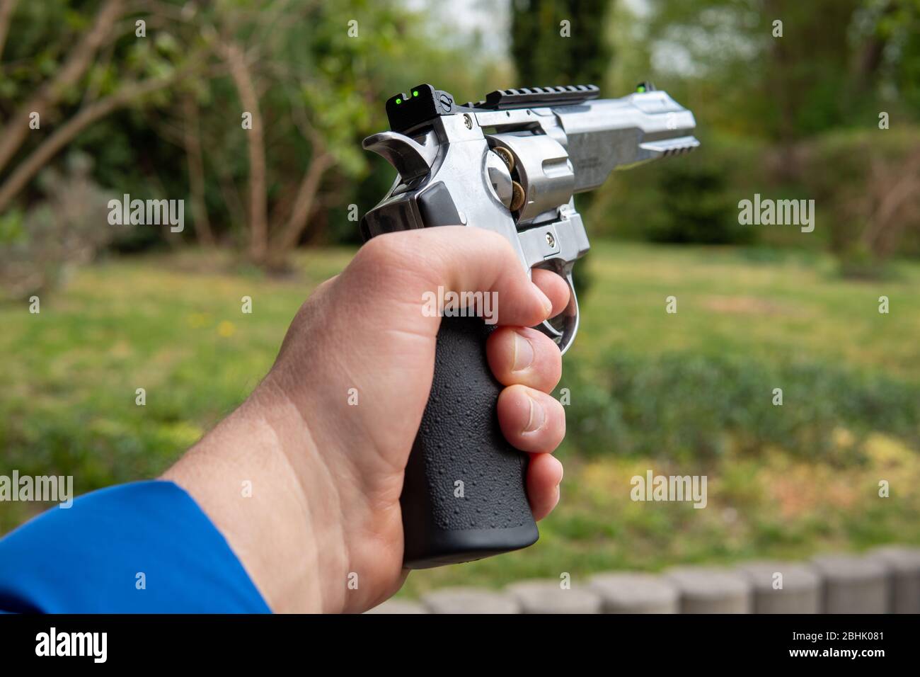 a left hand holds a big silver revolver in the air Stock Photo - Alamy