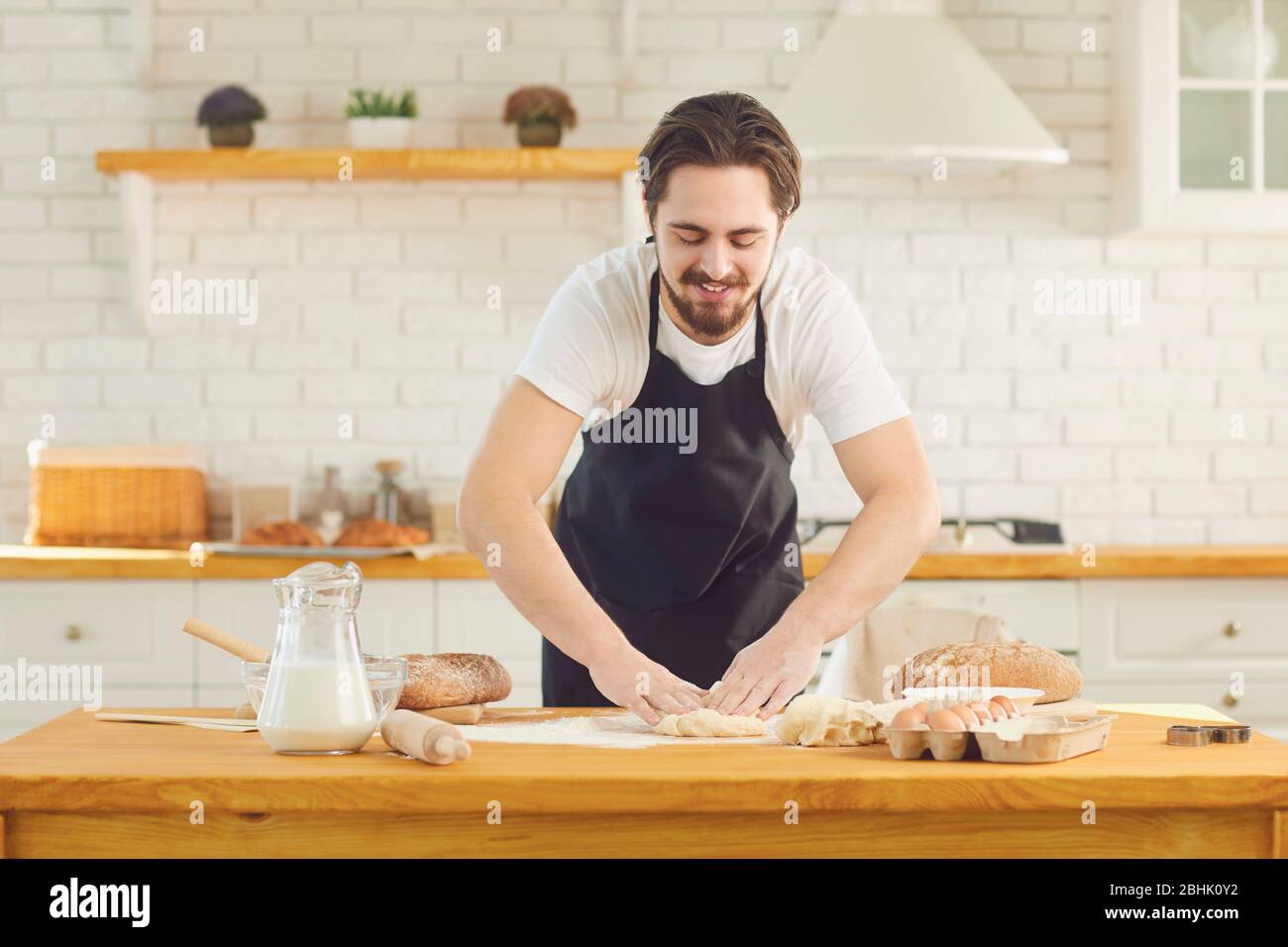 Baker male bearded man makes fresh bread dough while standing at a ...
