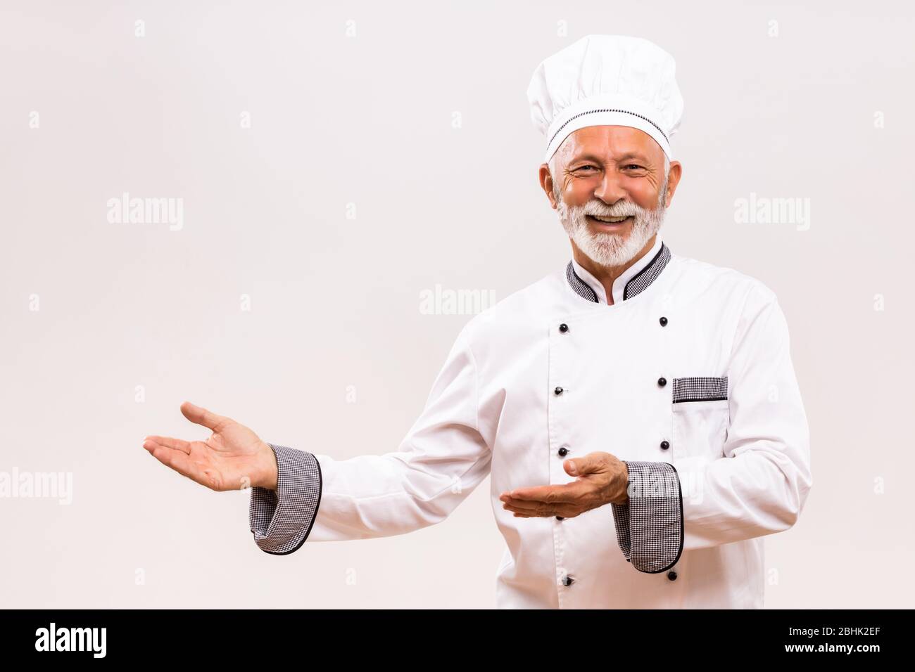 Portrait of senior chef showing welcome gesture Stock Photo - Alamy