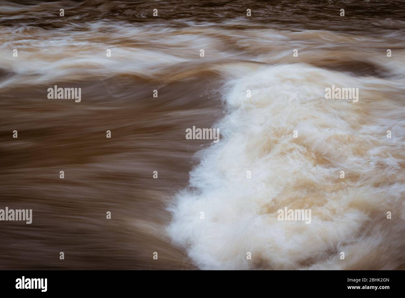Waves and fast flowing muddy water in a river in a long-exposure ...