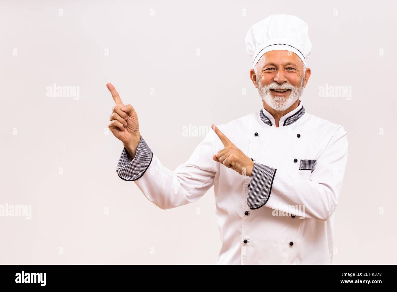 Portrait of senior chef pointing on gray background Stock Photo - Alamy