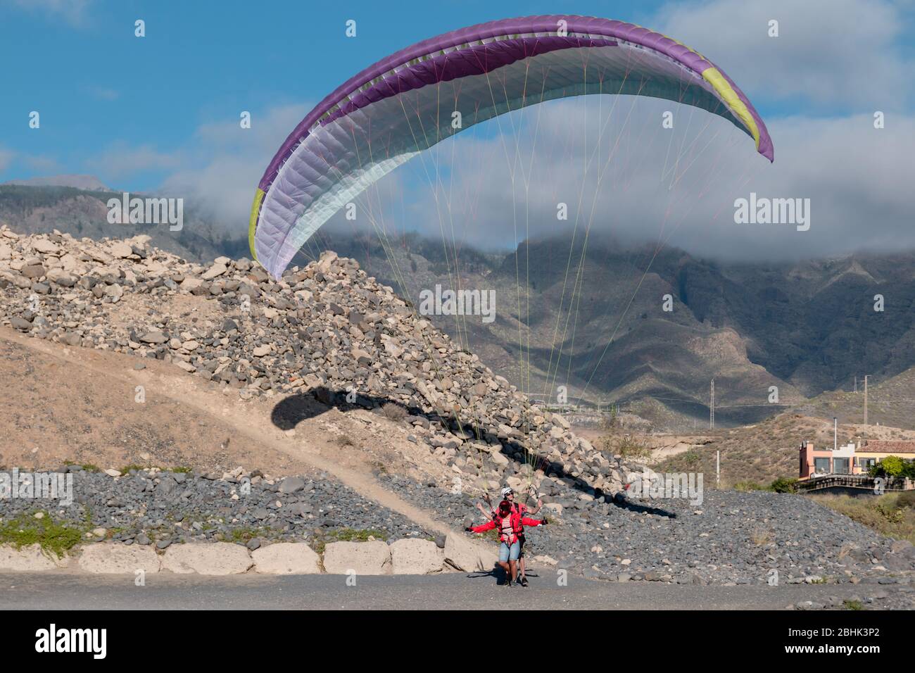 Paraglider with instructor pilot in tandem landing on the ground in ...
