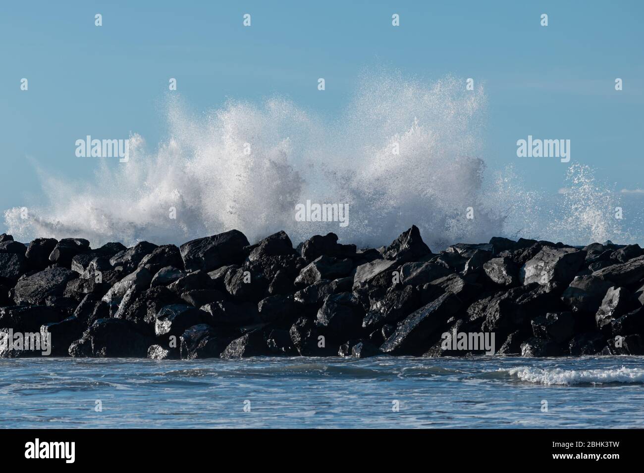 Rock groyne or breakwater in the sea, pounded by powerful waves ...