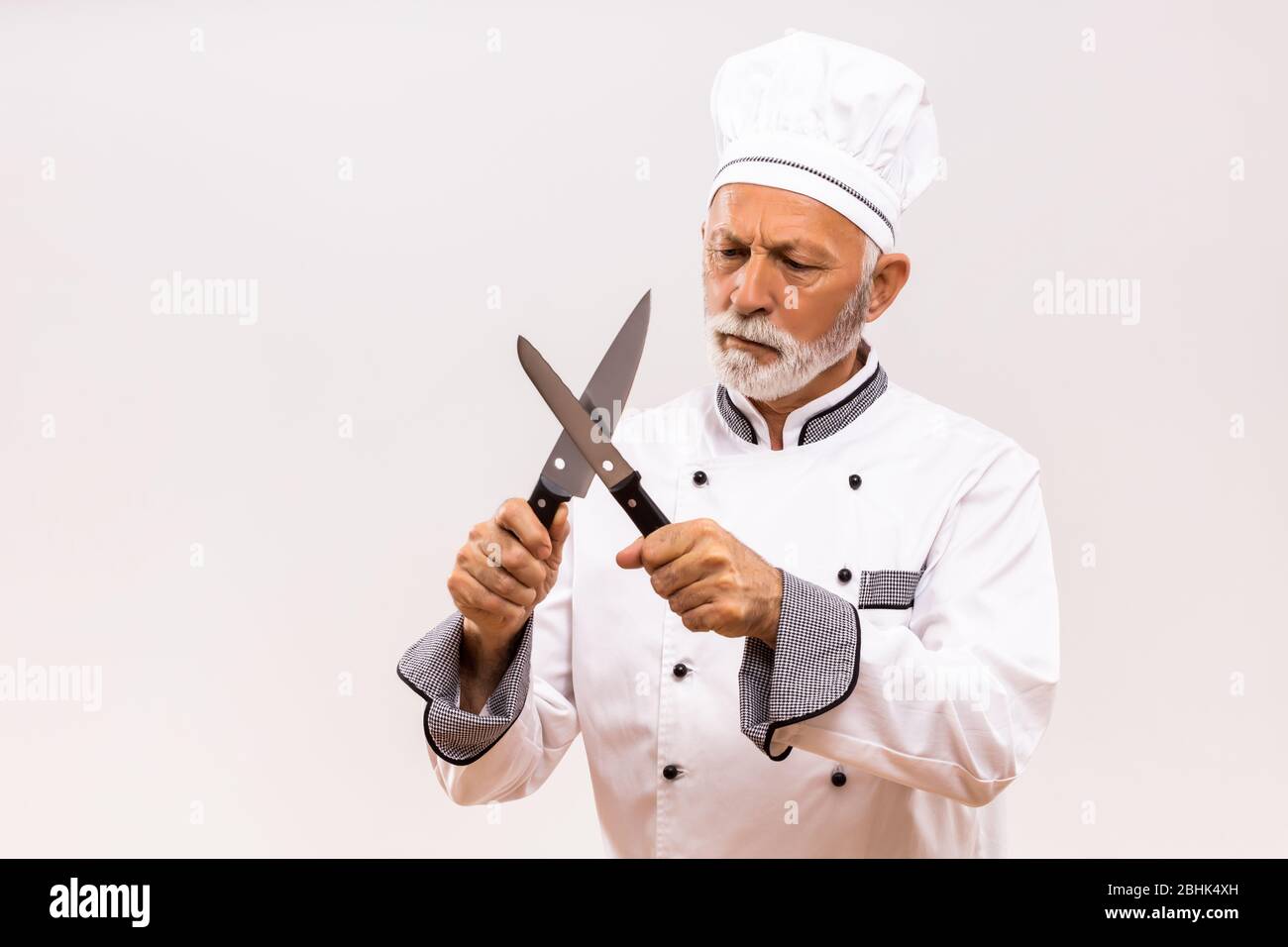 Image of angry chef sharpens knives on gray background Stock Photo - Alamy