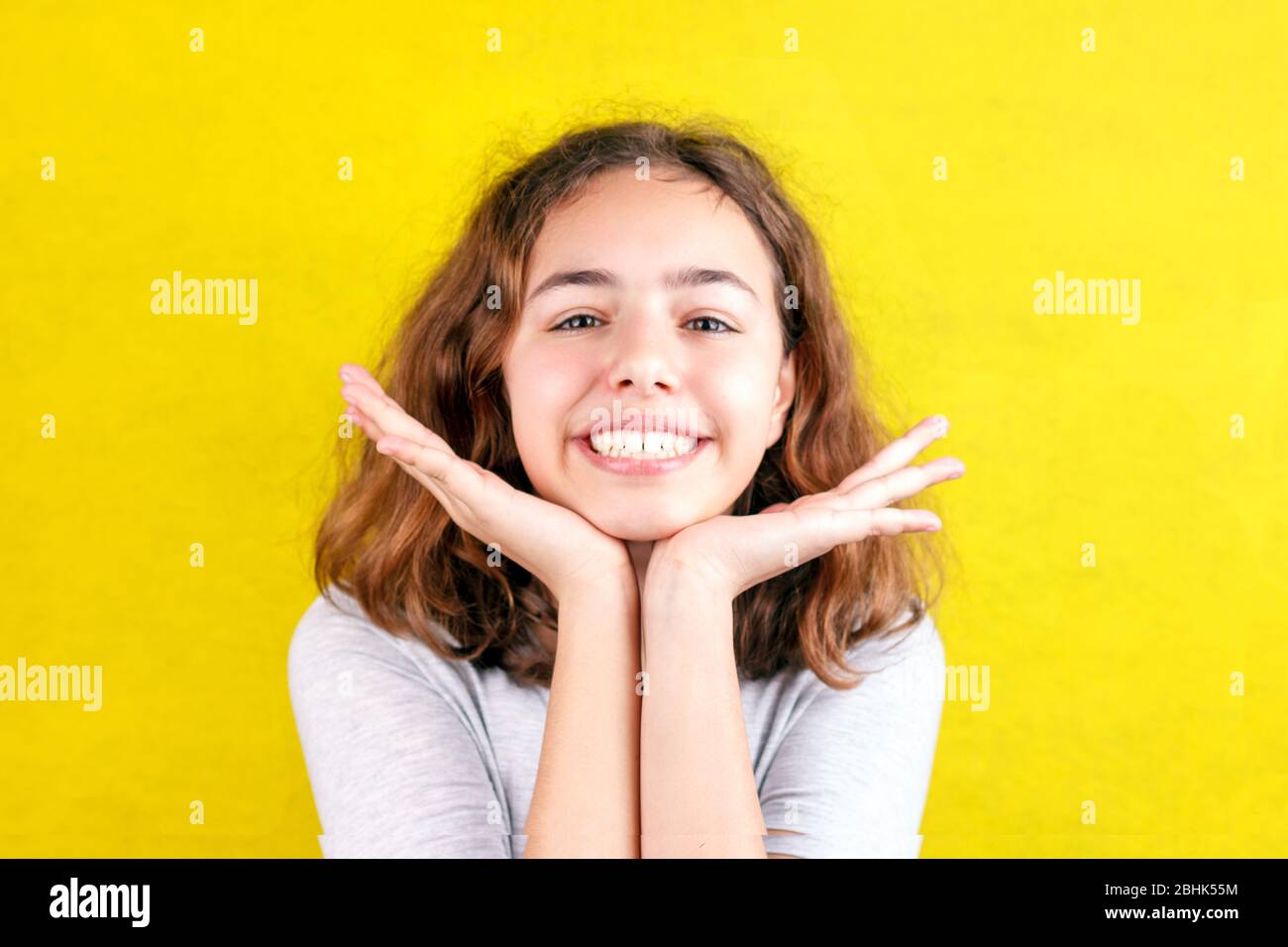Cute teenager girl with funny face smiling with big eyes. Palms on the ...