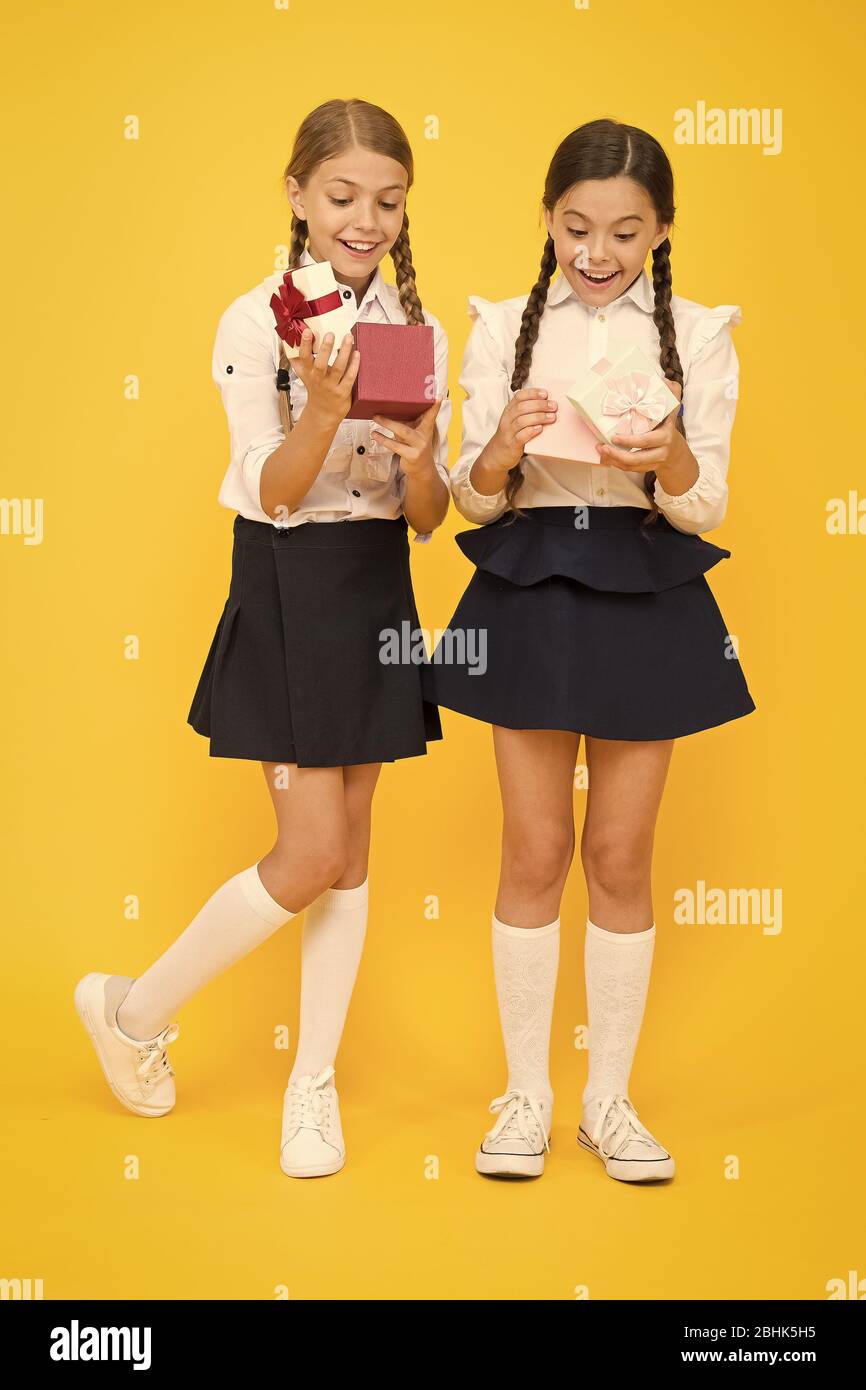 Girls opening gifts yellow background. Classmates tidy pupils open ...
