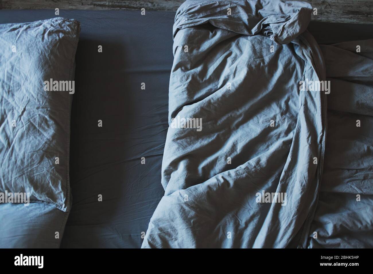 Top view crumpled bed in the morning after sleep. Gray cotton sheet and ...