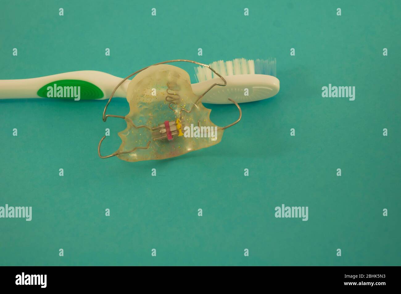 tooth correction plate, orthodontic retainer and toothbrush on a blue ...