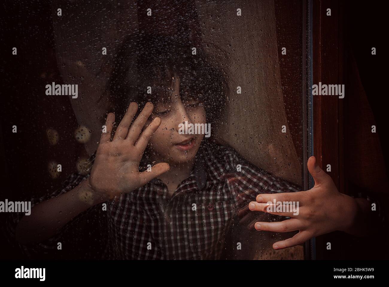 The boy behind the glass in raindrops Stock Photo - Alamy