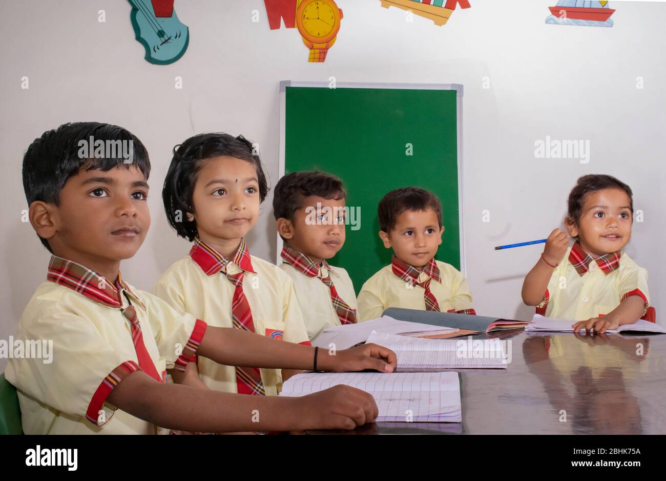 Young primary or elementary school children sitting at their desks in a ...