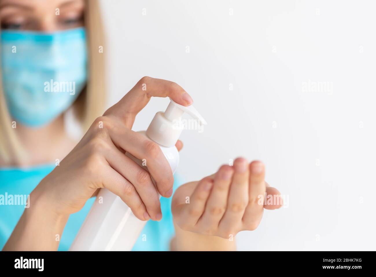 Female doctor or nurse in uniform puts a disinfectant soap on her hands ...