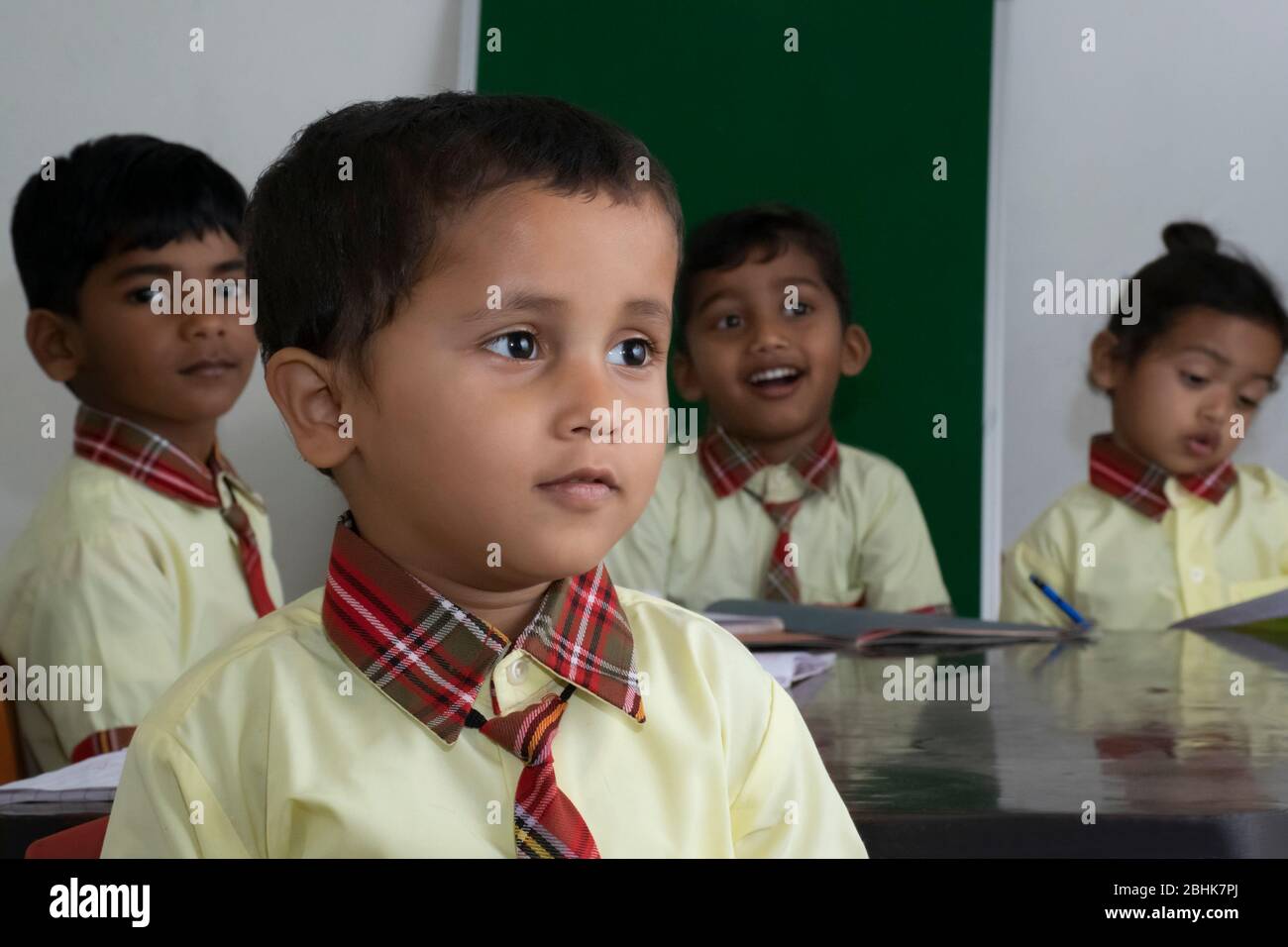 Young primary or elementary school children sitting at their desks in a ...